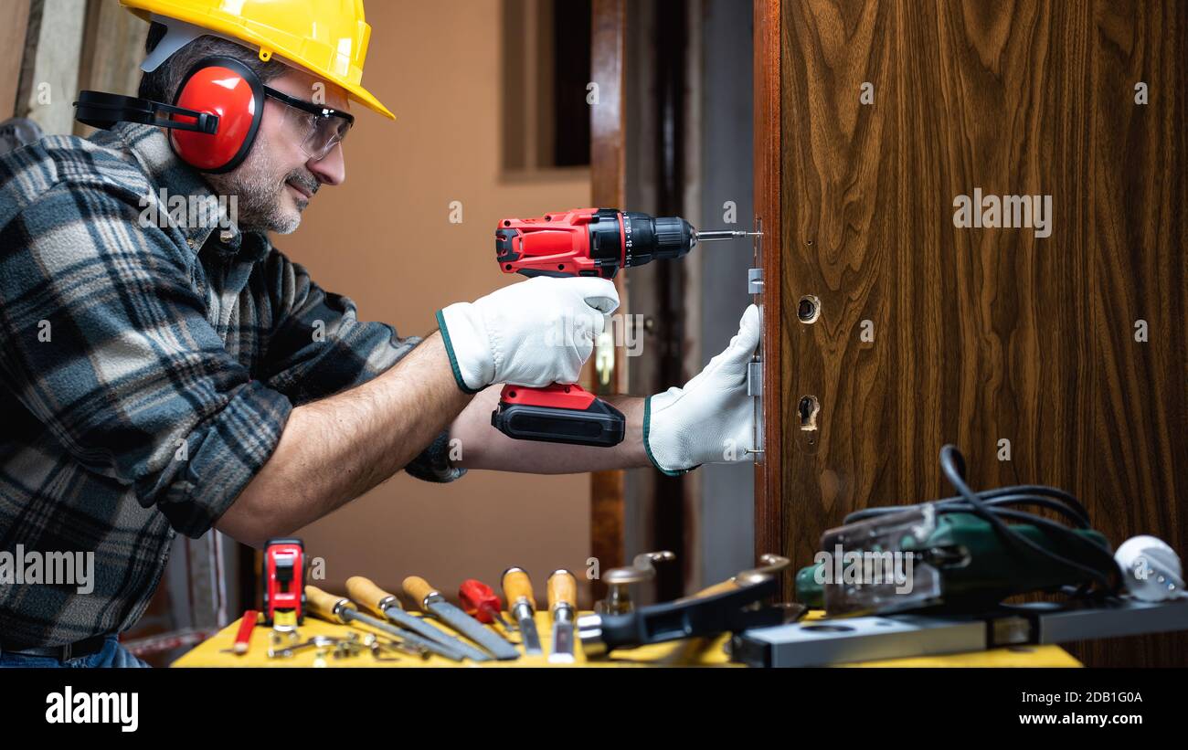 Close-up. Carpenter at work repairs and installs the new lock of a ...
