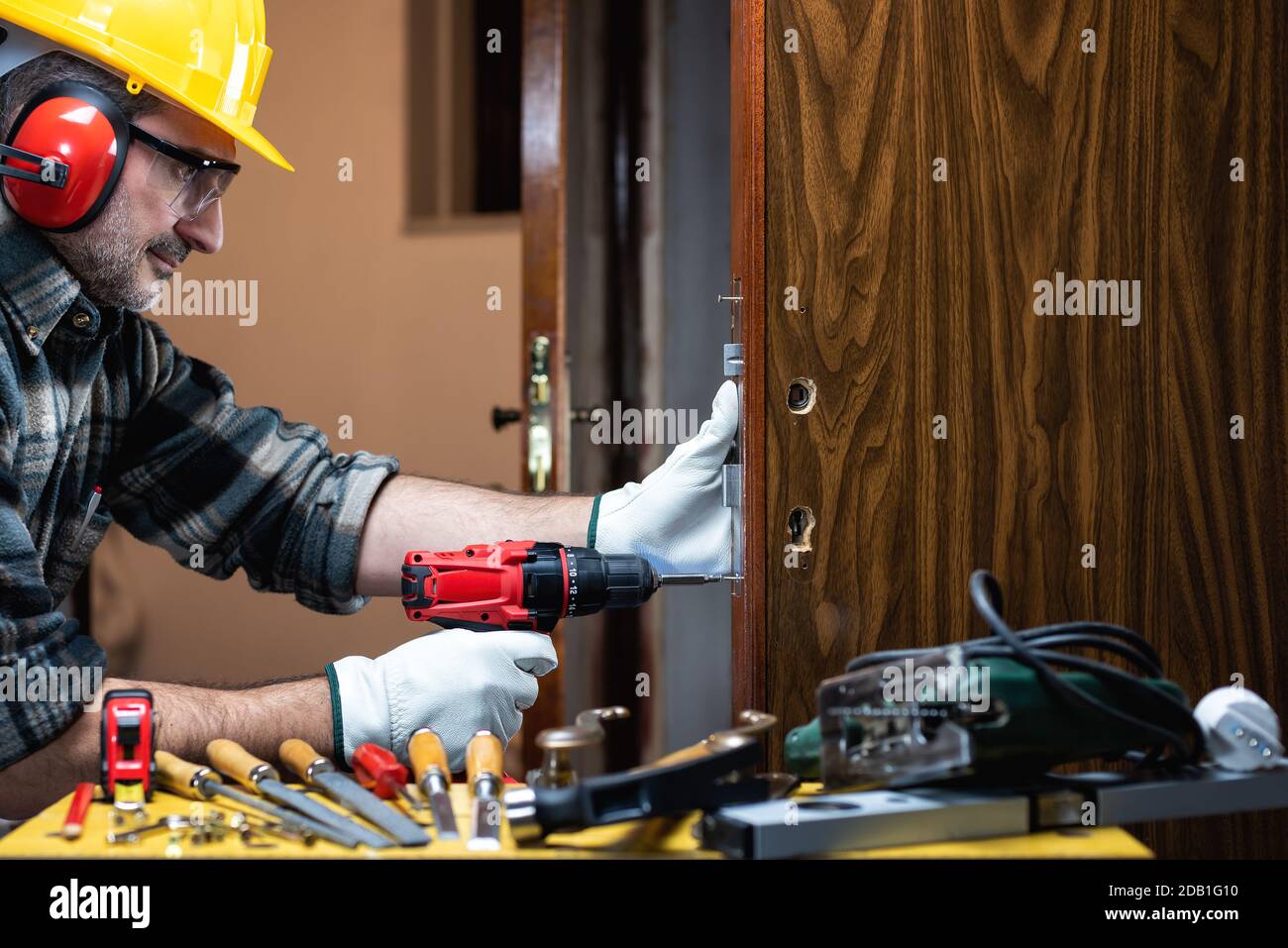 Close-up. Carpenter at work repairs and installs the new lock of a ...