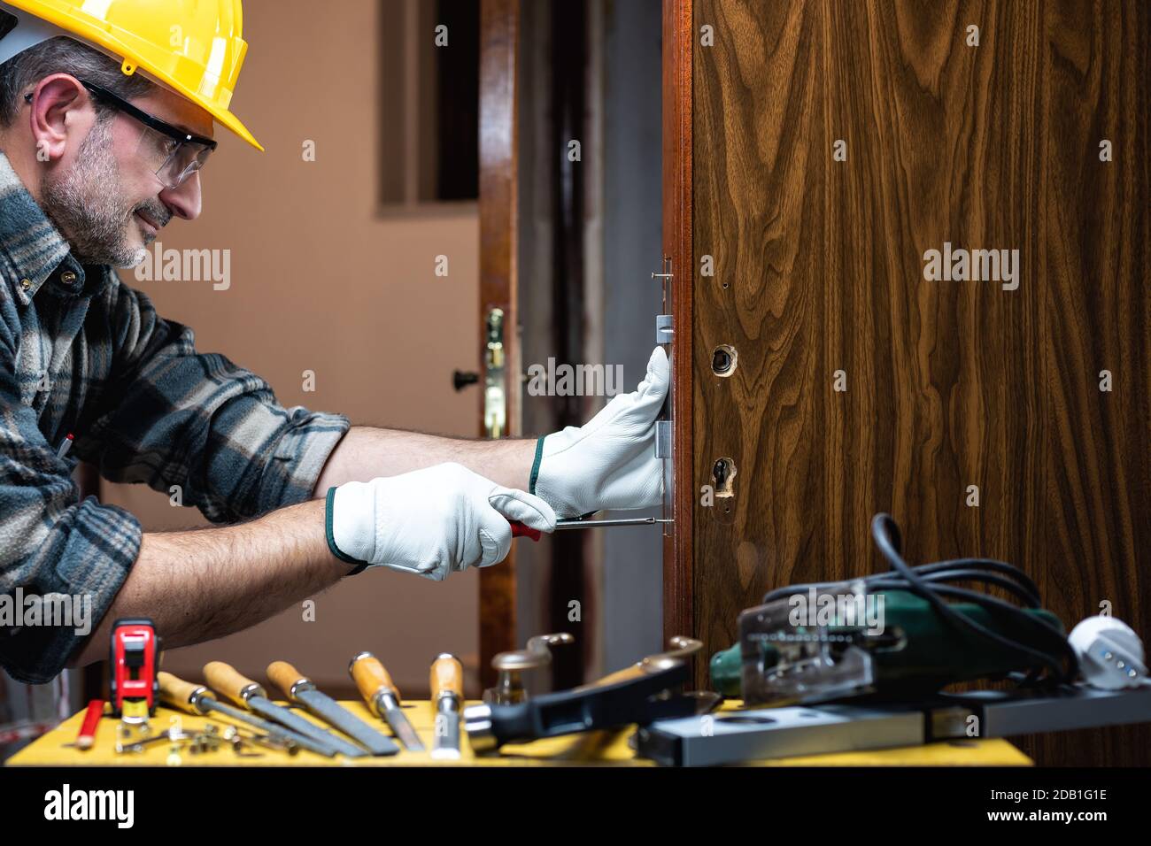 Close-up. Carpenter at work repairs and installs the new lock of a ...
