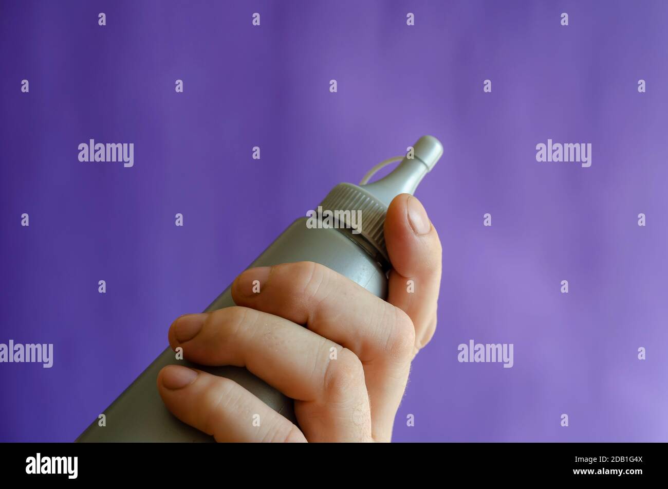 Male hand and gray plastic bottle of syrup. The man is holding a new ...