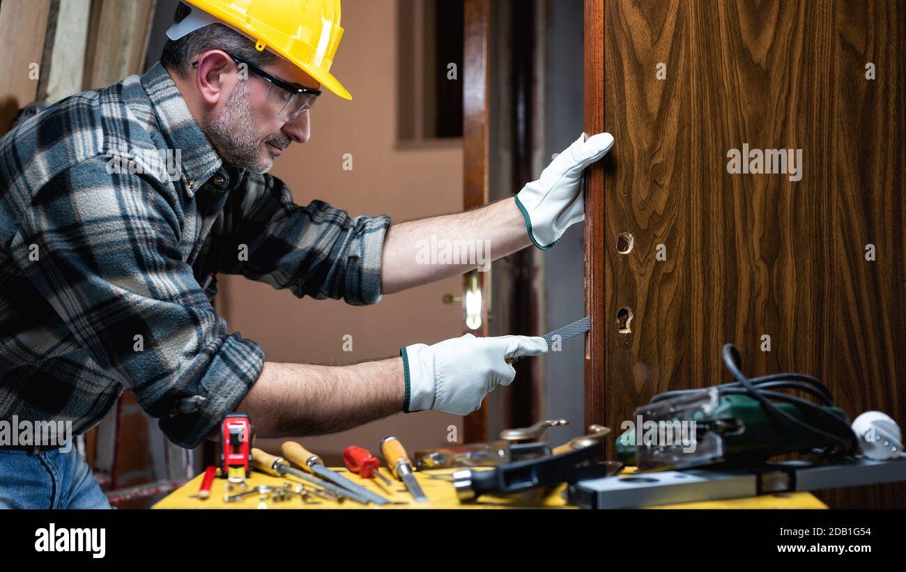Close-up. Carpenter at work repairs and installs the new lock of a ...