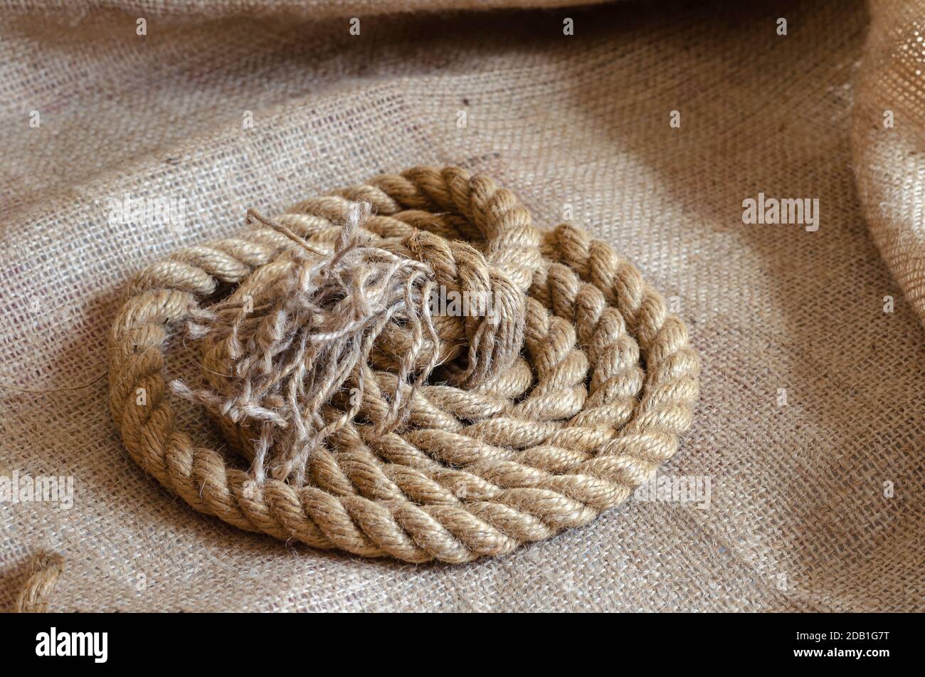 Thick natural rope wound in a reel on sackcloth. Close-up of a laid ...