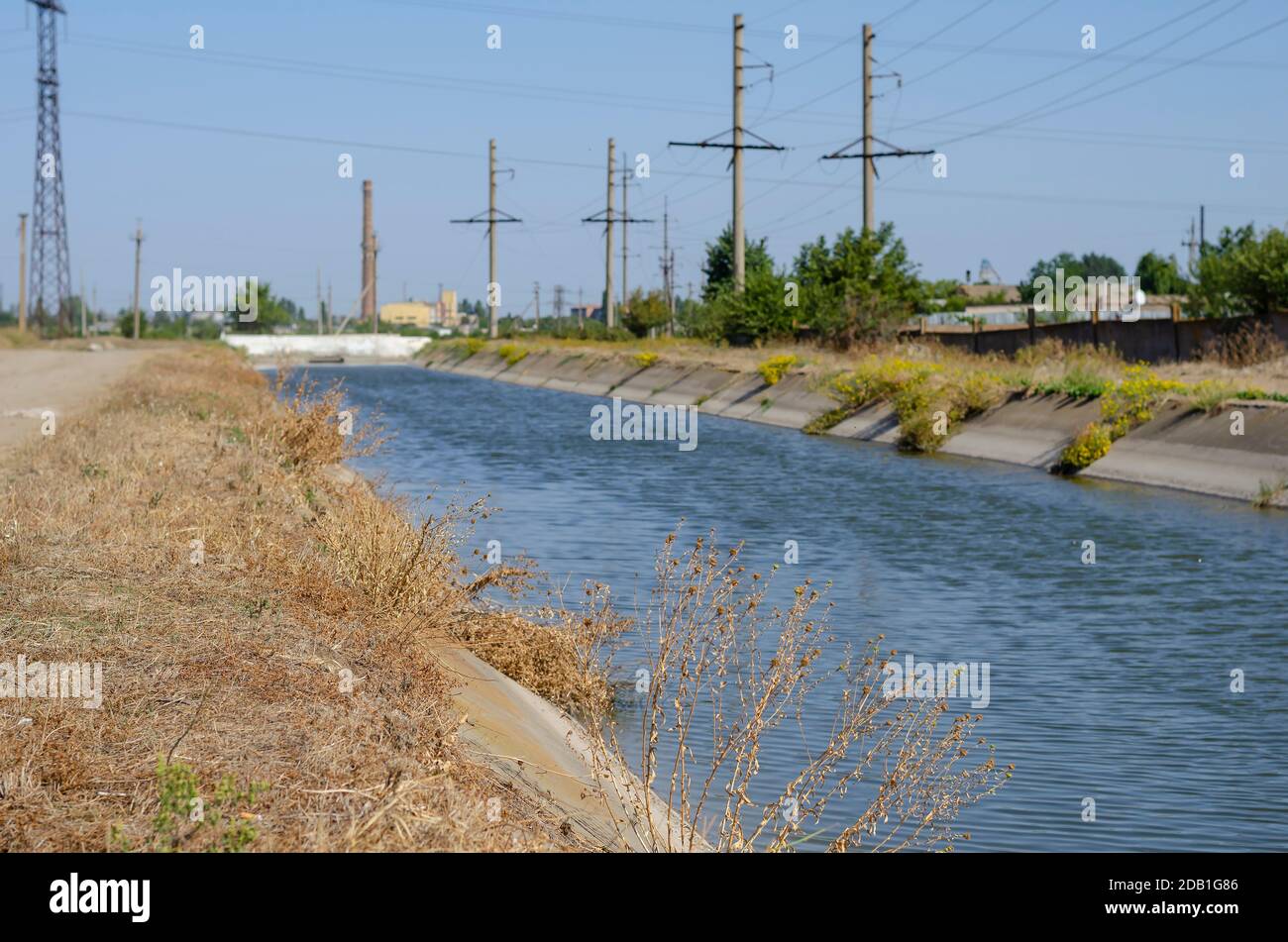 Irrigation agricultural channel with water. Power line along the canal ...