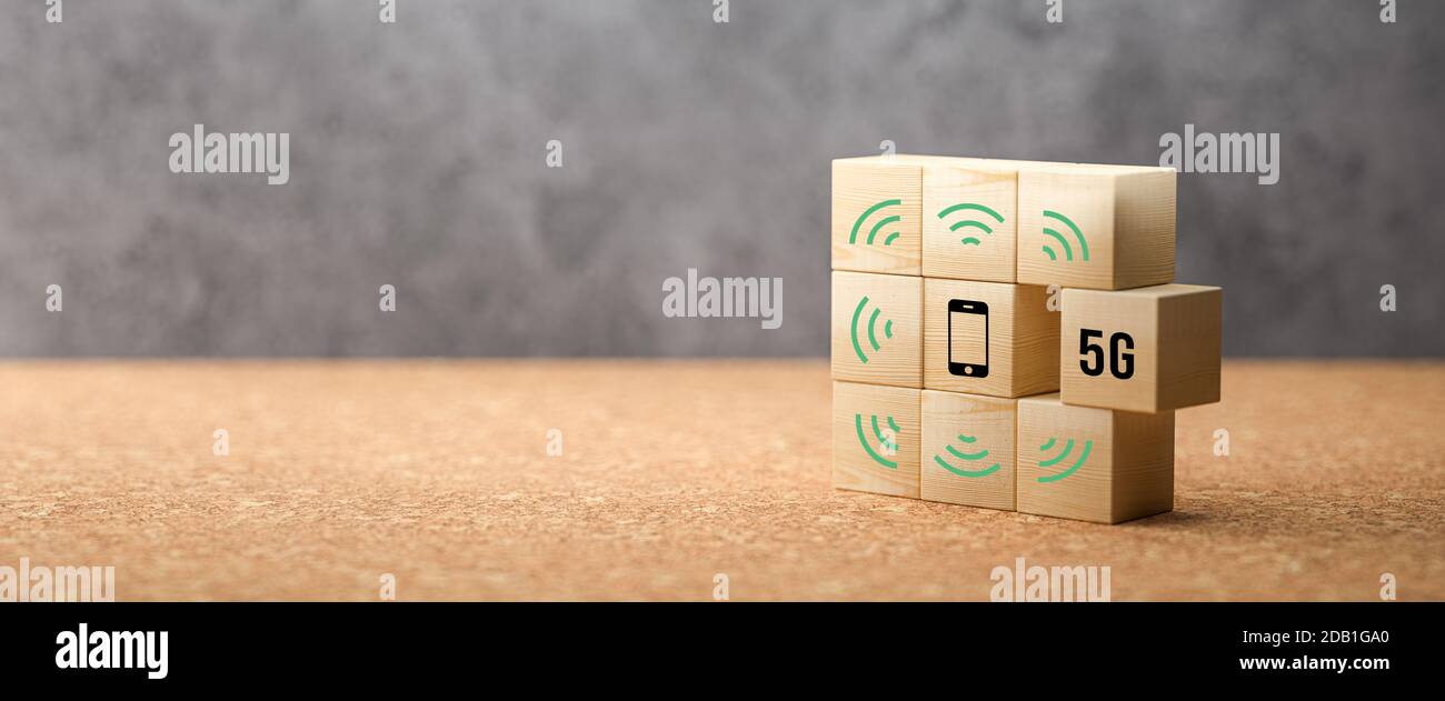 cubes with 5G and smartphone symbol on cork surface and concrete ...