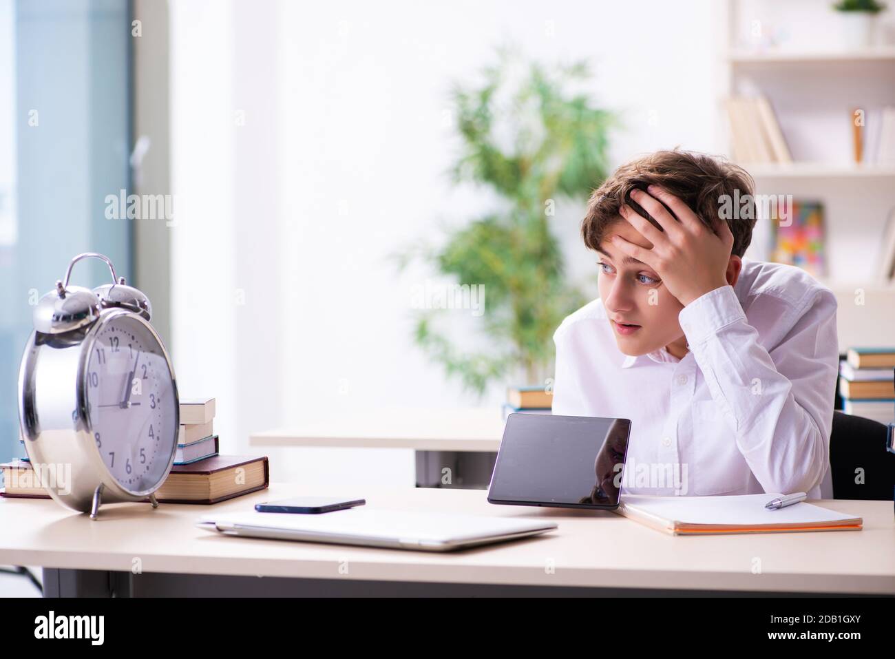 Schoolboy in punctuality concept in the classroom Stock Photo - Alamy
