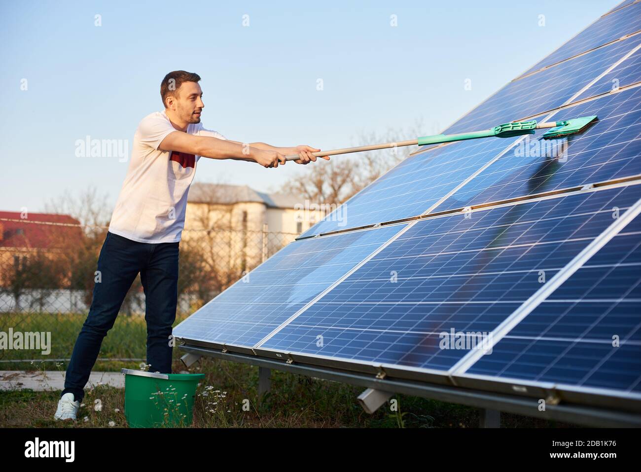 Man is cleaning solar panel on a plot near the house. Male worker is ...