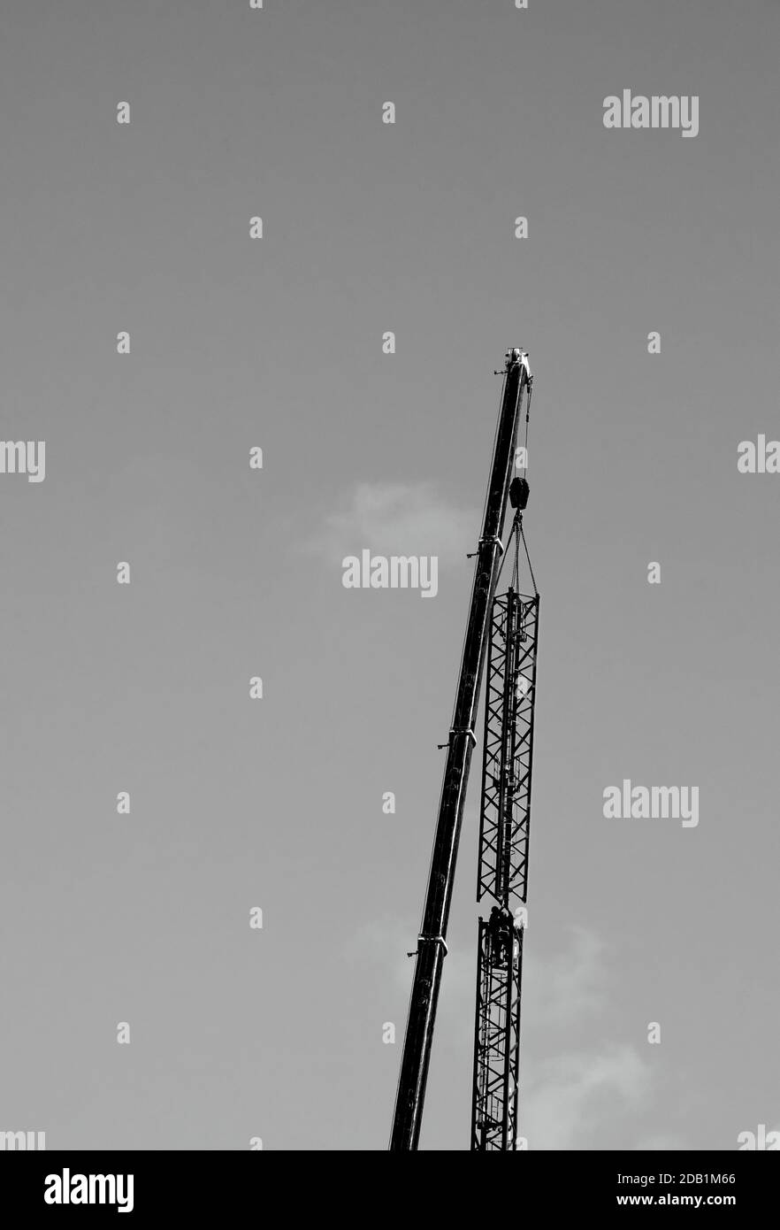 Two riggers mounting tower crane at construction site. Industrial ...