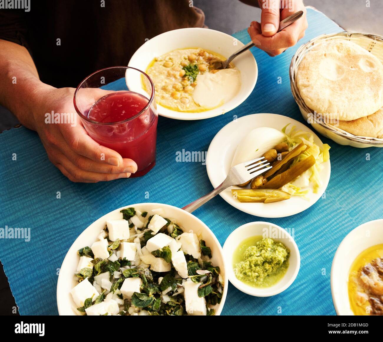 Man eating fresh warm hummus with pita bread, pickles, feta cheese ...
