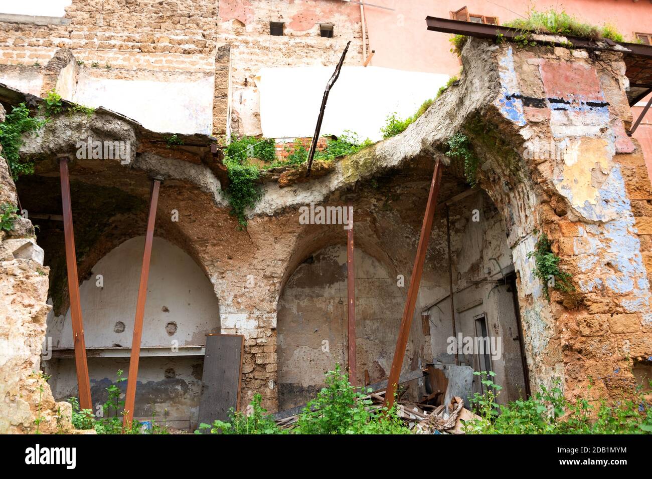Abandoned ruined house near residential building. Broken stone wall and ...