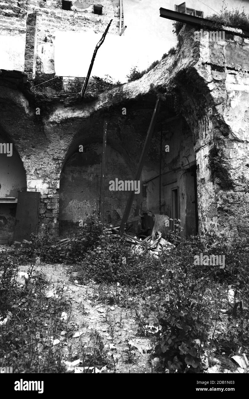 Abandoned ruined house near residential building. Broken stone wall and ...