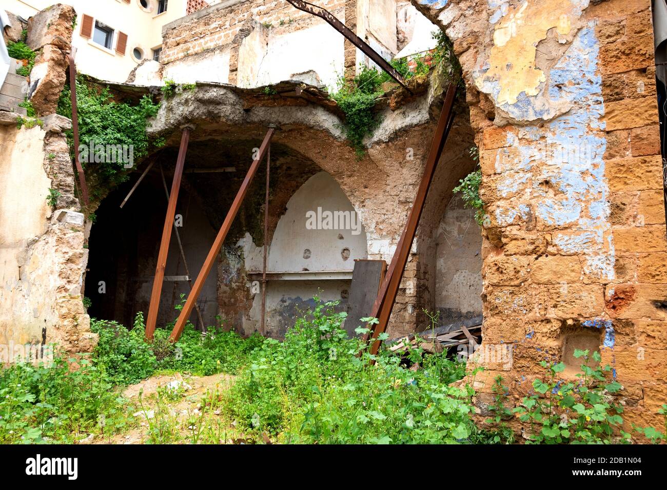 Abandoned ruined house near residential building. Broken stone wall and ...