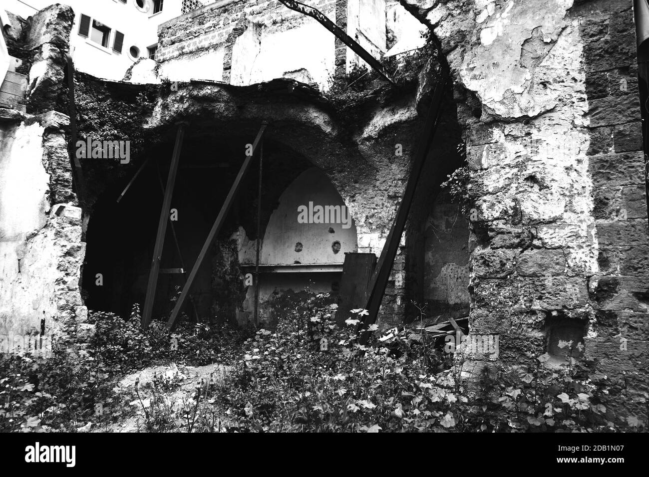 Abandoned ruined house near residential building. Broken stone wall and ...