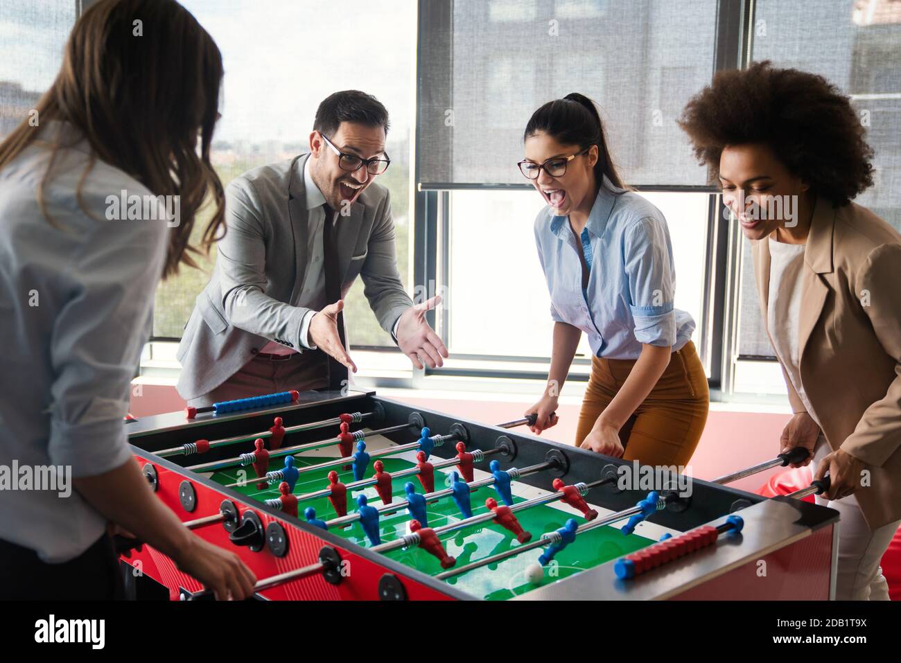 Coworkers playing table football on break from work Stock Photo - Alamy