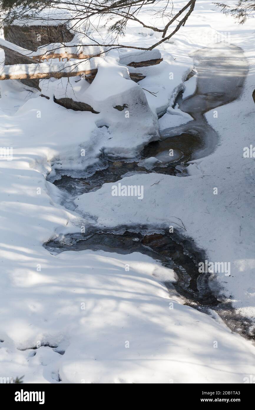Warren falls - frozen creek under ice and snow with rocky shores. Sunny ...