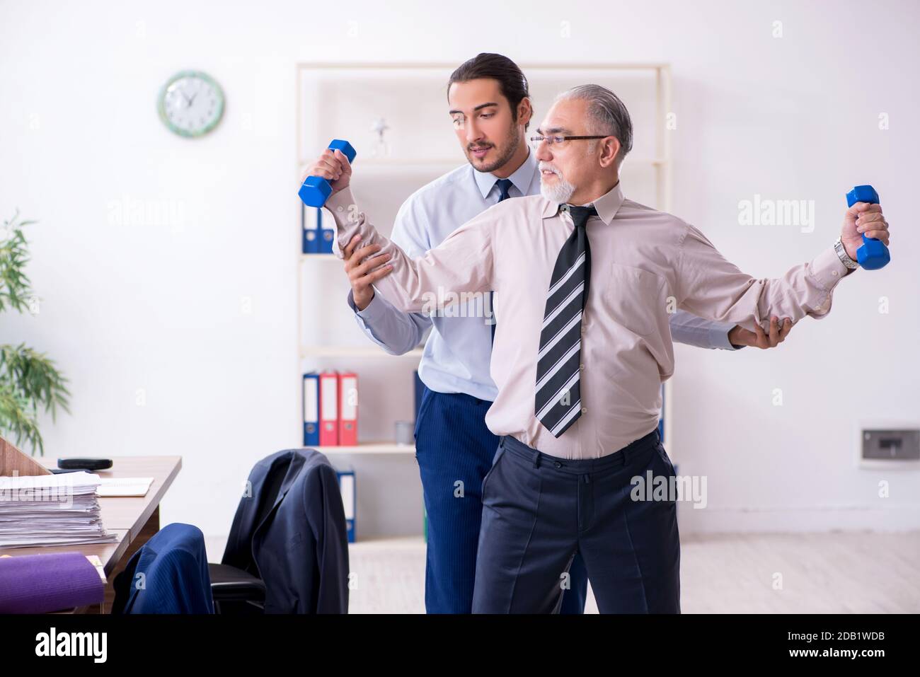 Two employees doing physical exercises at the workplace Stock Photo - Alamy