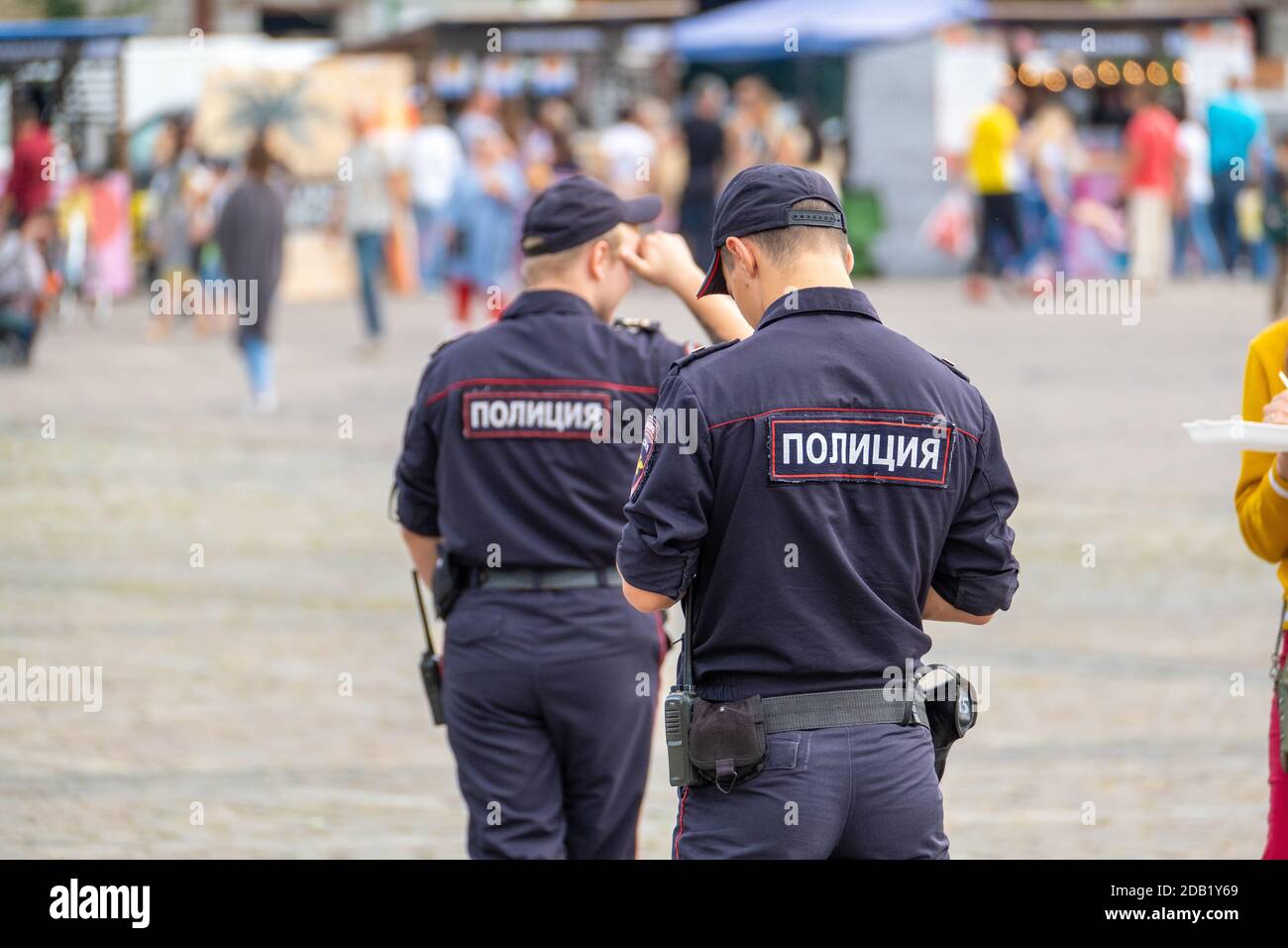 Police officers patrolling square during fair Stock Photo - Alamy