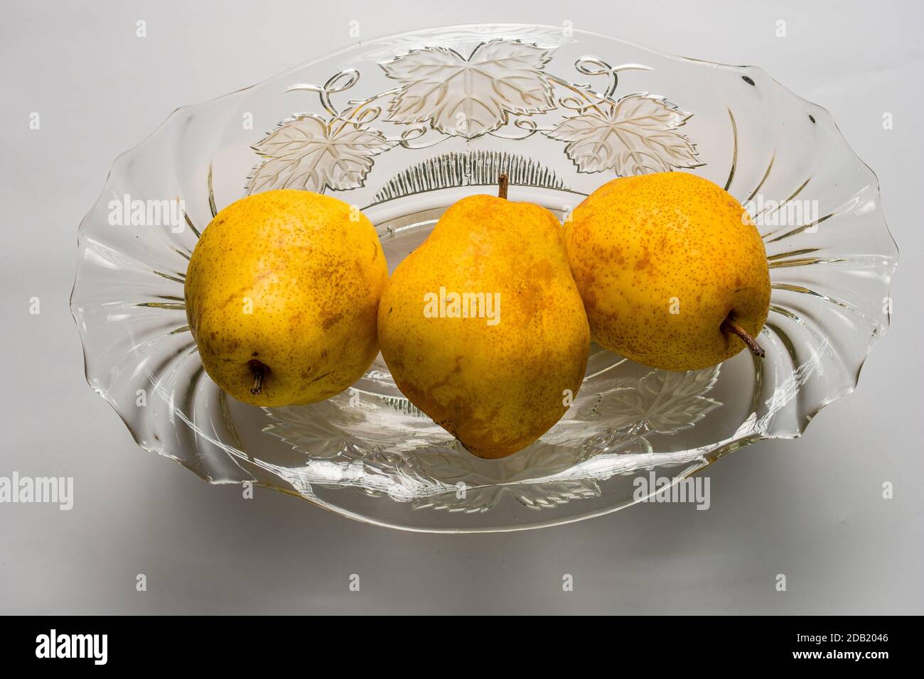 Still life with three yellow pears in an antique glass bowl Stock Photo ...