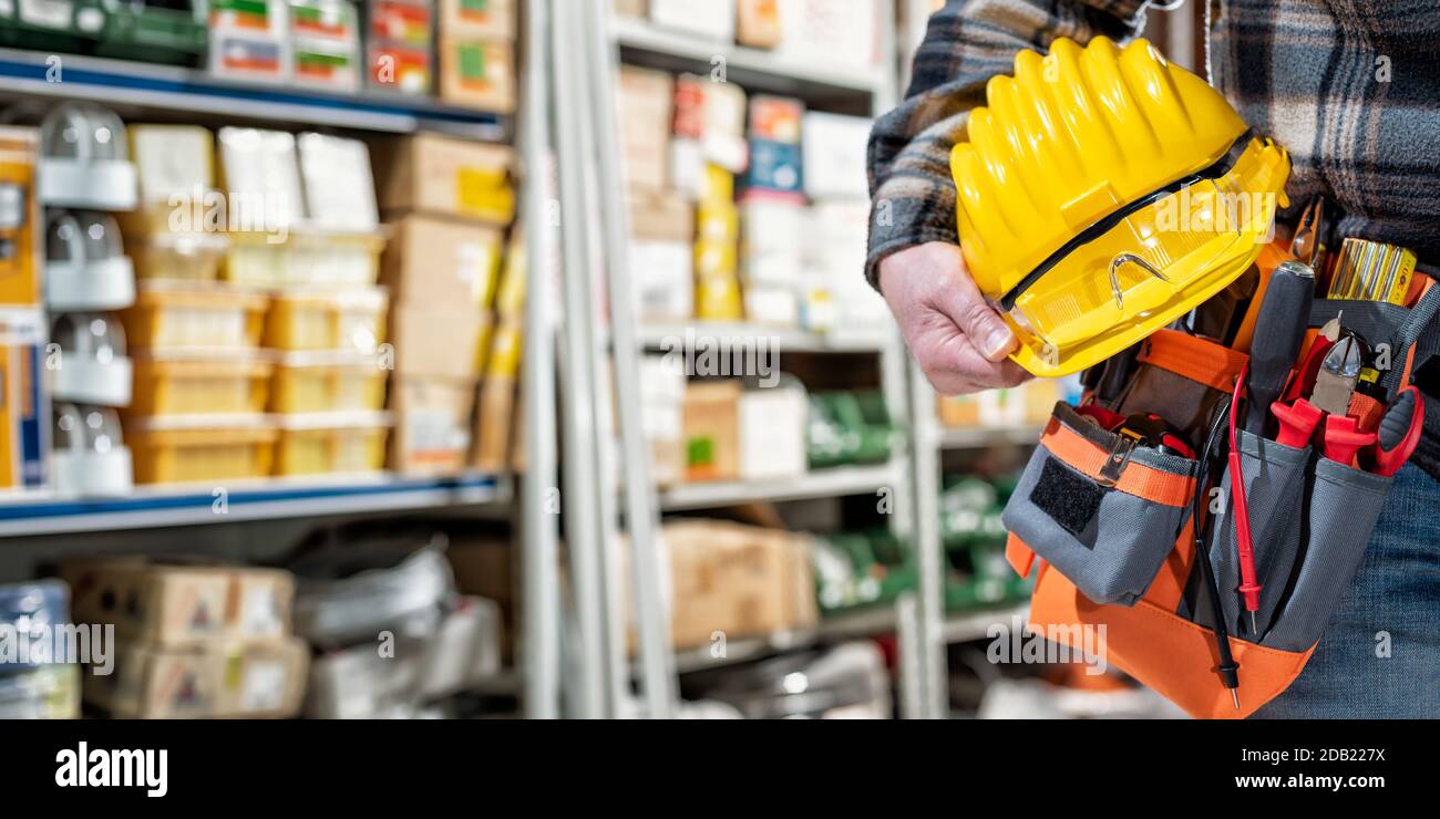 Electrician in the electrical component store holds the helmet and ...