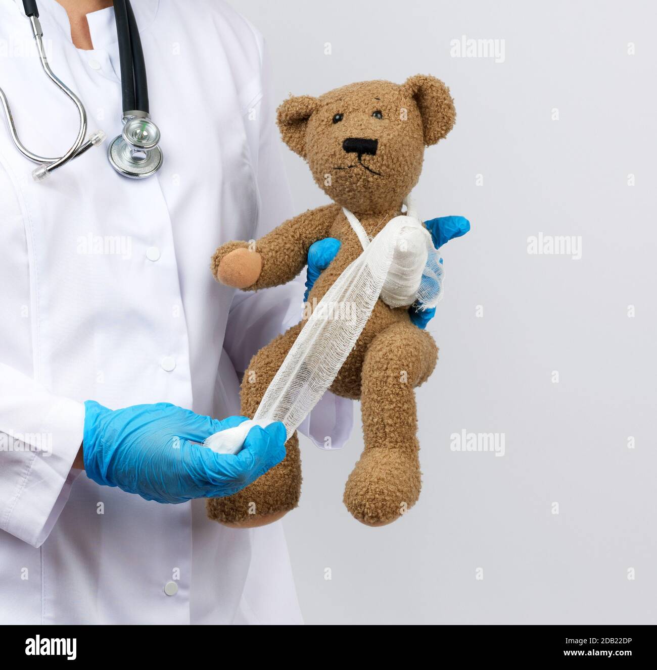 female medic holds brown teddy bear and bandages paw with white gauze ...