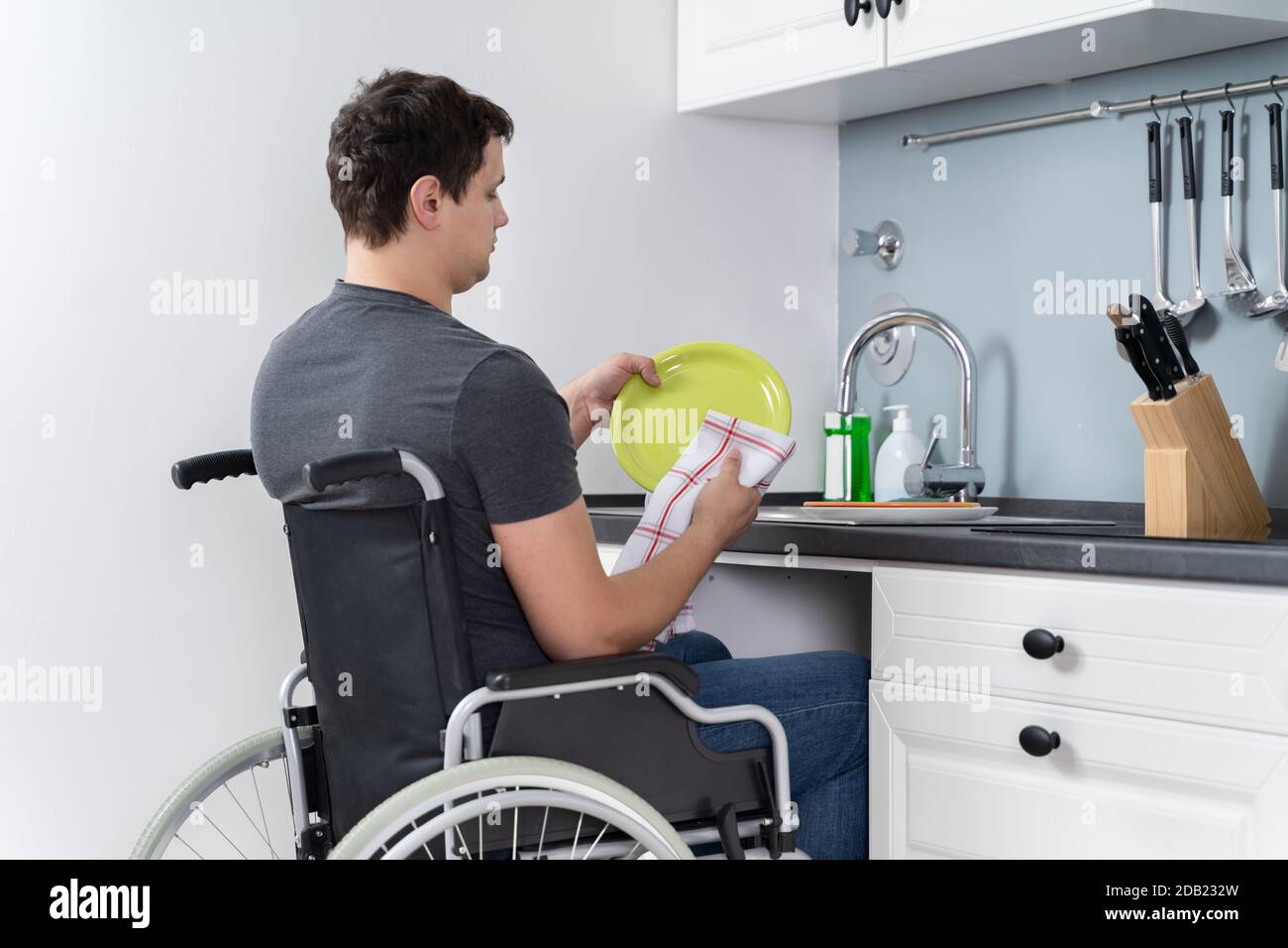 Handicapped Man Sitting On Wheelchair Washing And Cleaning Dishes In ...