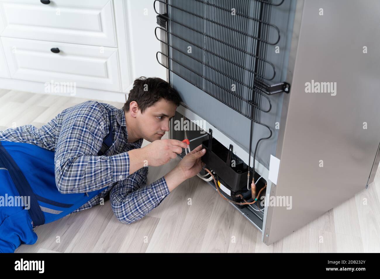 Male Worker Repairing Refrigerator With Screwdriver In House Stock ...