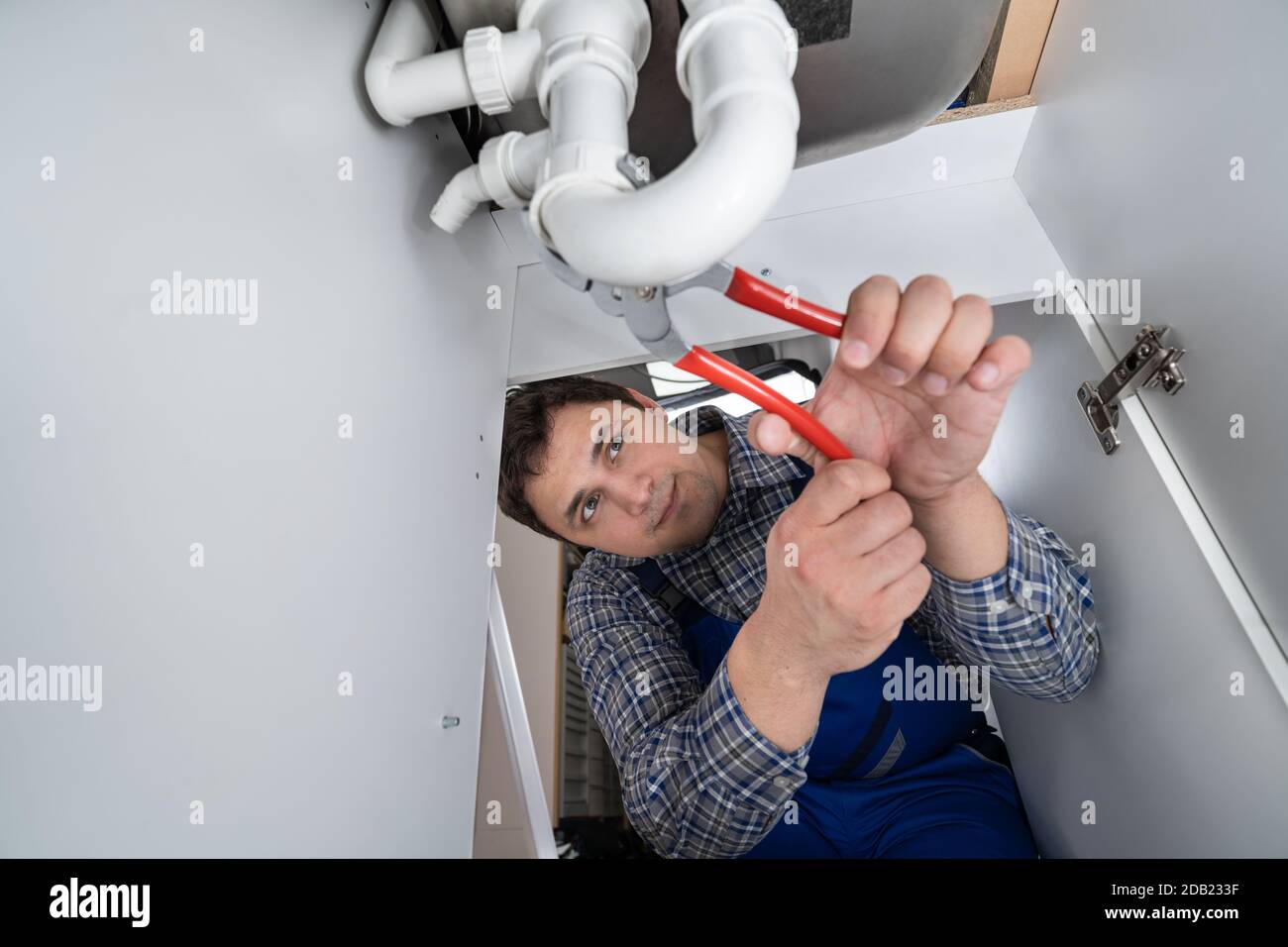 Young Plumber Working With Pipe Wrench In Kitchen Stock Photo - Alamy