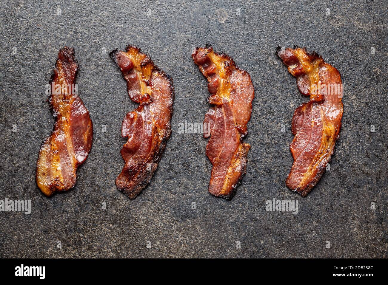 Fried bacon. Sliced roasted bacon on old kitchen table. Top view Stock ...