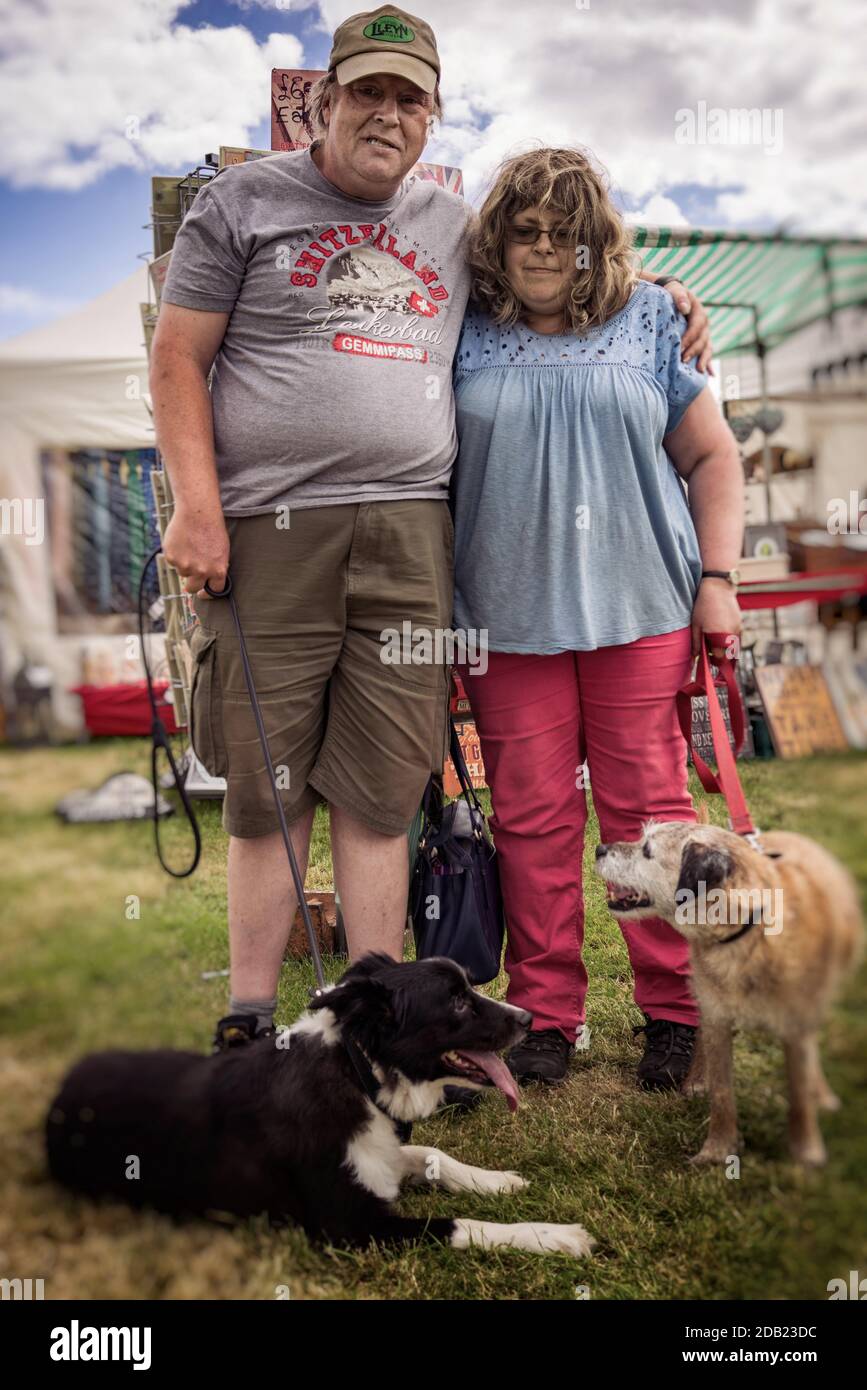 A middle aged couple at a dog show in the summer with their two dogs ...