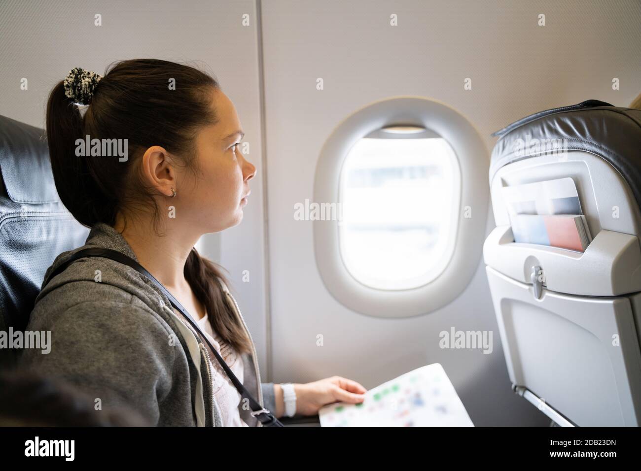 Young Woman Sitting In Airplane Looking In Window Stock Photo - Alamy