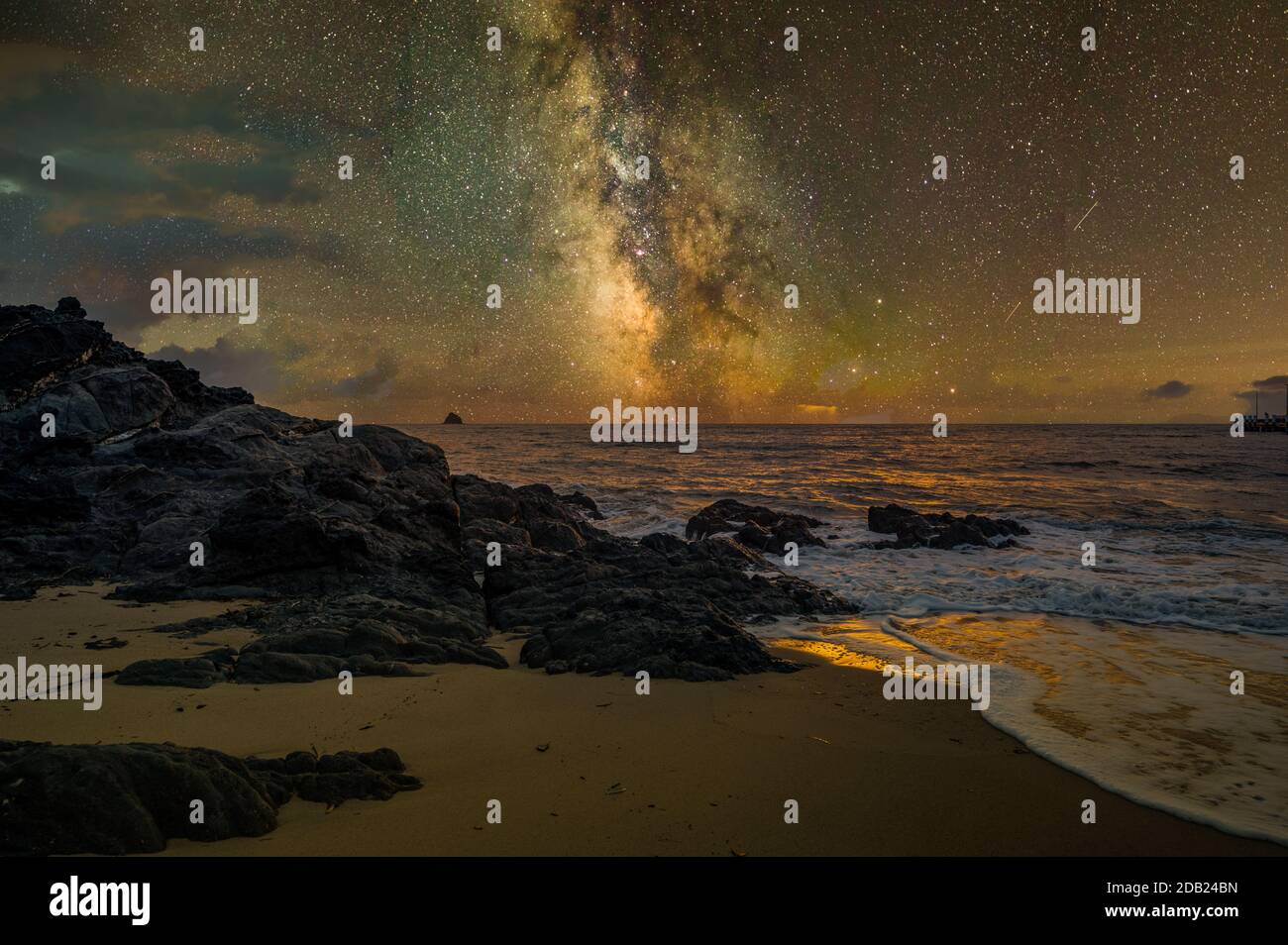 The ocean waves hitting the rocky beach and gleaming under the night ...