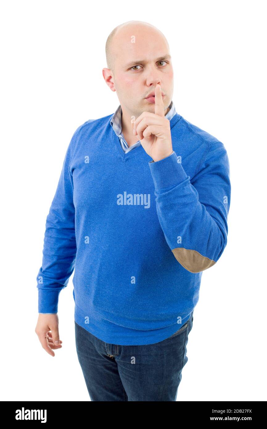 portrait of a young bald man making a shushing gesture with his finger ...