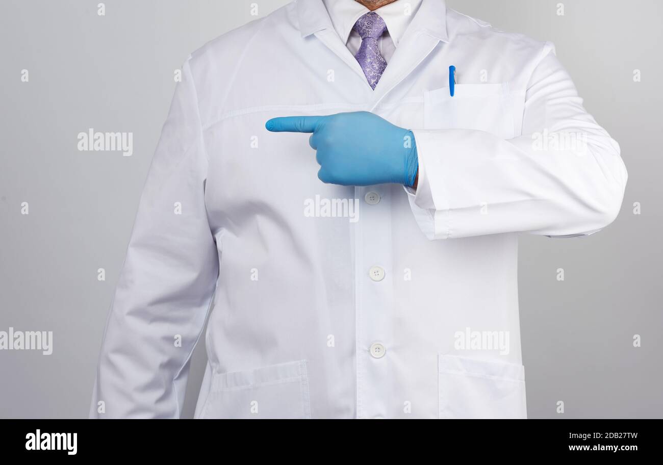 medic man in white coat with buttons, on hands wearing blue sterile ...