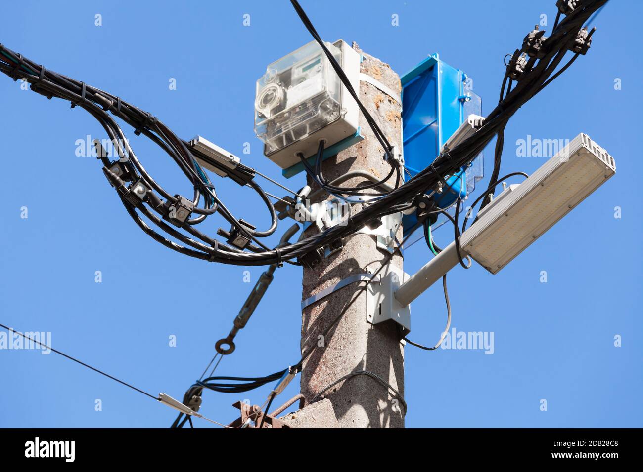 Top of a power pole with street light, electric meter and wires is ...