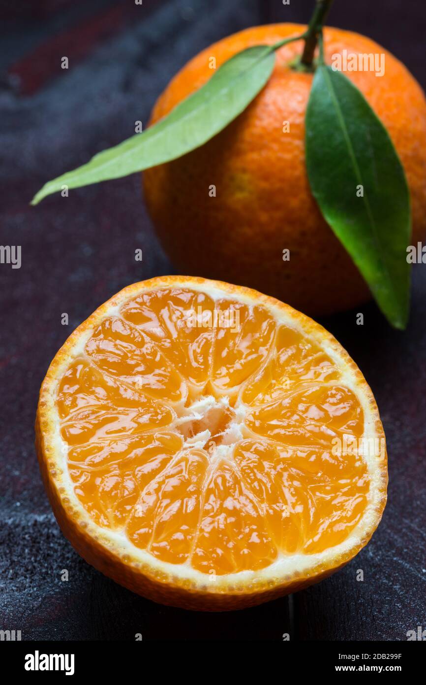 Mandarin cut open on mahogany wooden background Stock Photo - Alamy