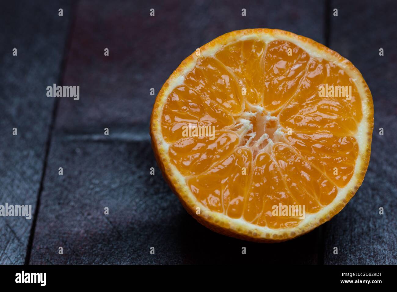 Mandarin cut open on mahogany wooden background Stock Photo - Alamy
