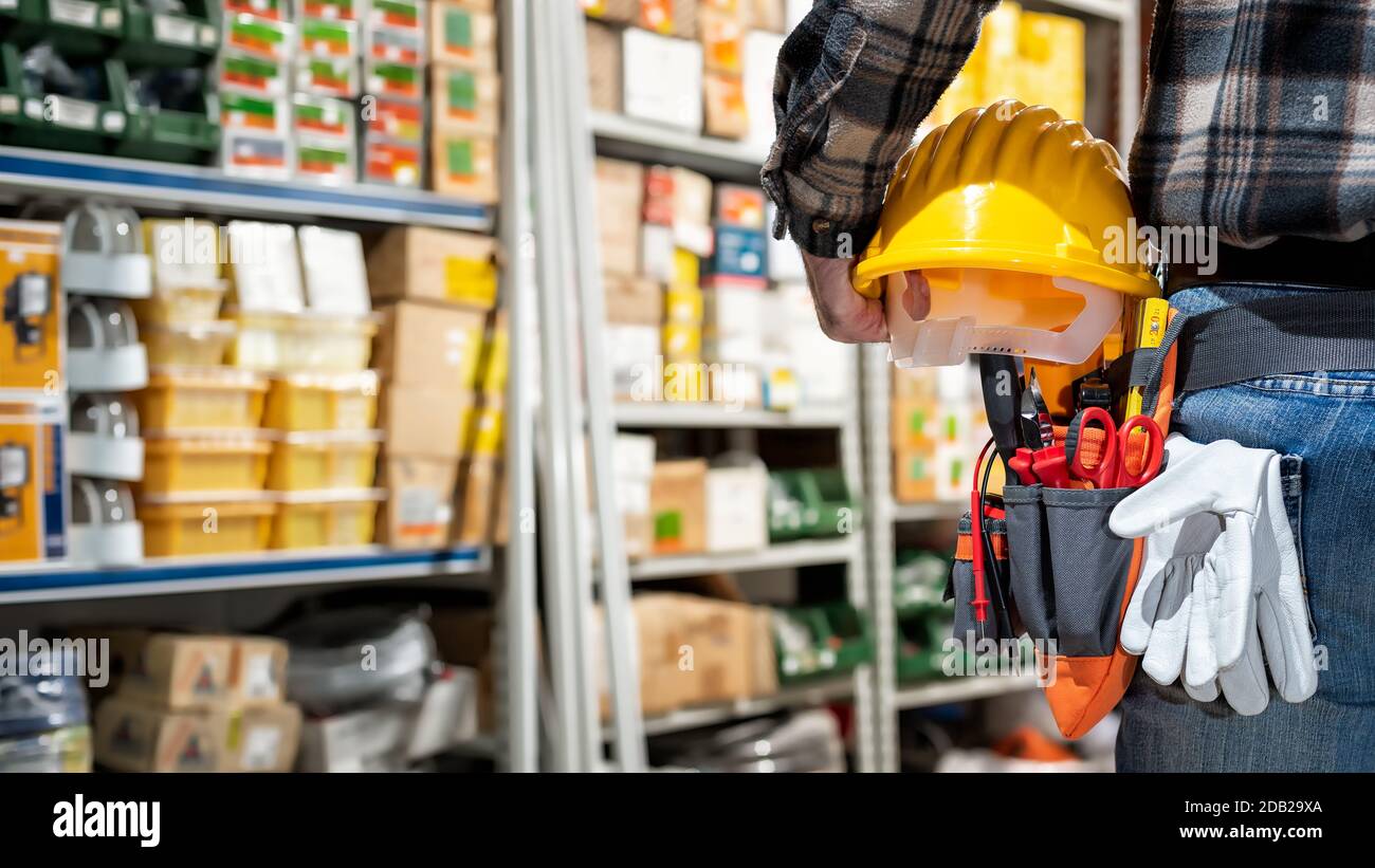 Electrician in the electrical component store holds the helmet and ...