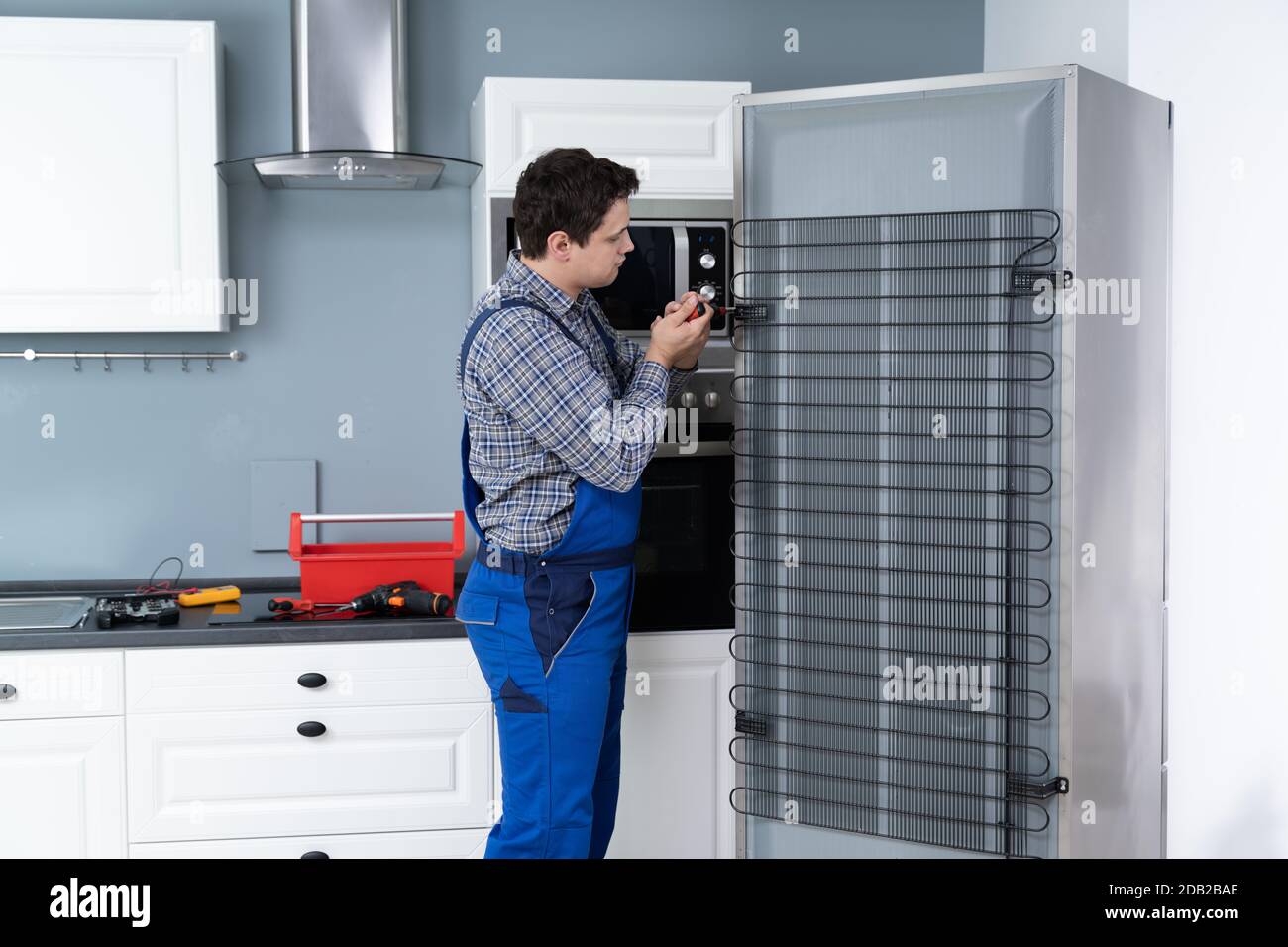 Male Worker Repairing Refrigerator With Screwdriver In House Stock ...