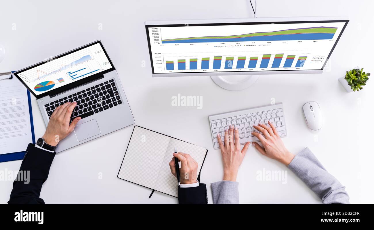 Two Businesspeople Examining Graph On Computer At Workplace Stock Photo ...