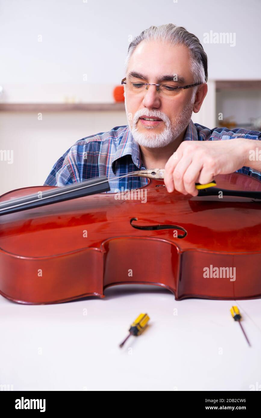 Senior repairman repairing musical instruments at home Stock Photo - Alamy