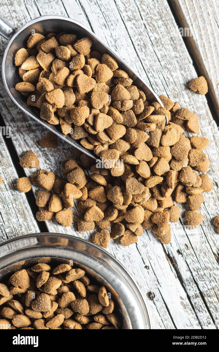 Dried kibble pet food in scoop. Heart shape dried animal food on old ...