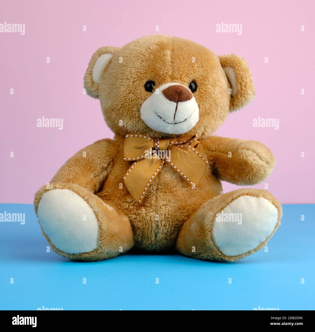 cute little brown teddy bear, toy is sitting on a blue background ...