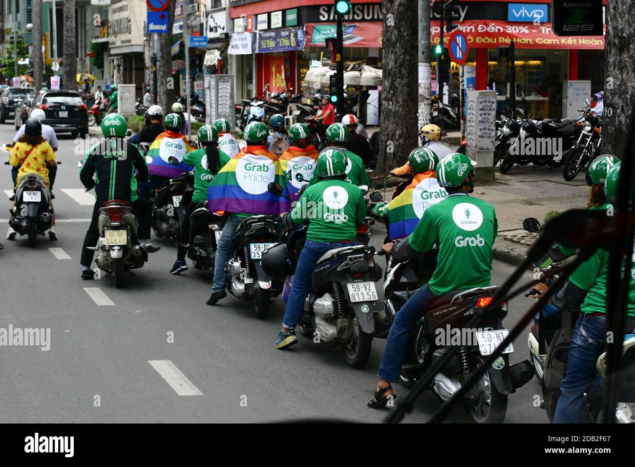 group of Taxi grabbike grab drivers in traffic with rainbow flag ...