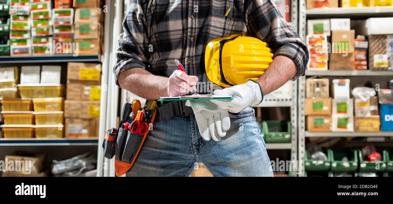 Electrician in the electrical components store writes on the notebook ...