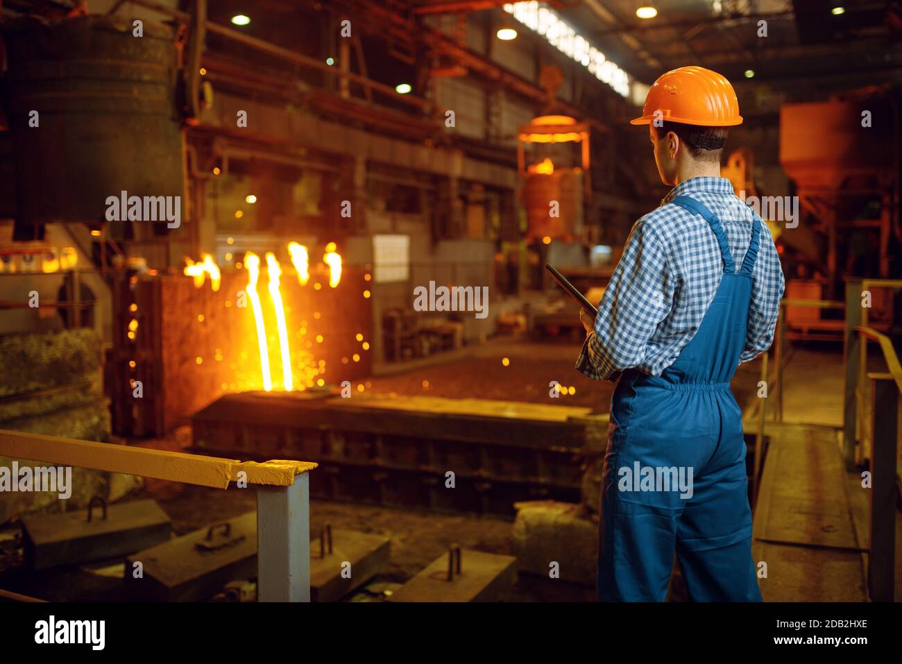 Master steelmaker in helmet at furnace with liquid metal, steel factory ...