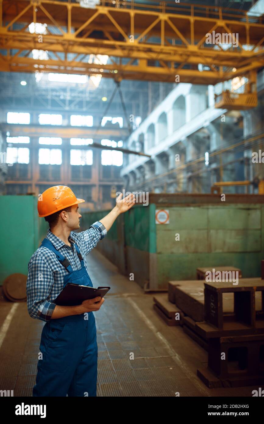 Master looks at the work of the crane operator on metal factory ...