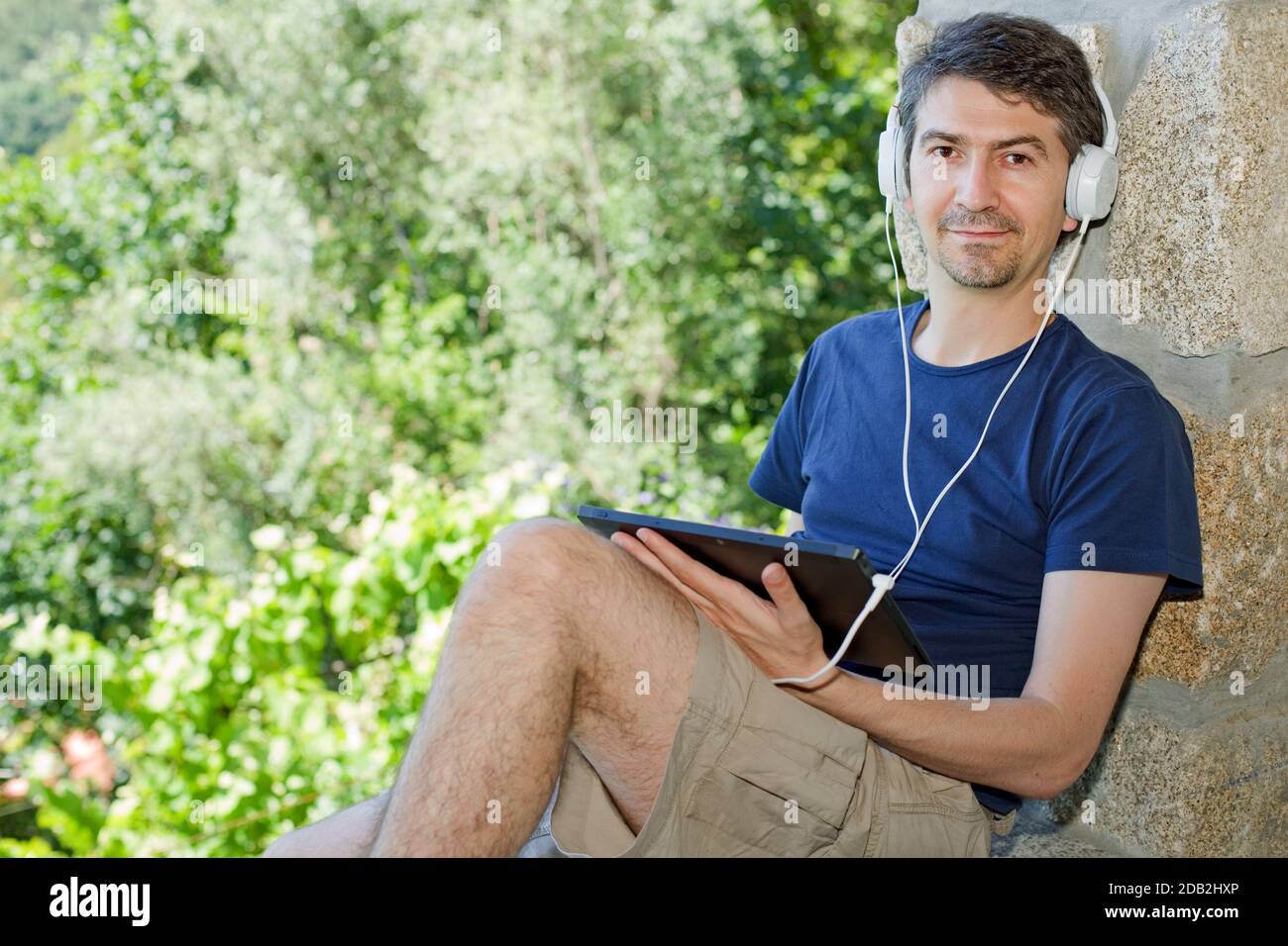 young man holding a tablet with headphones, outdoor Stock Photo - Alamy