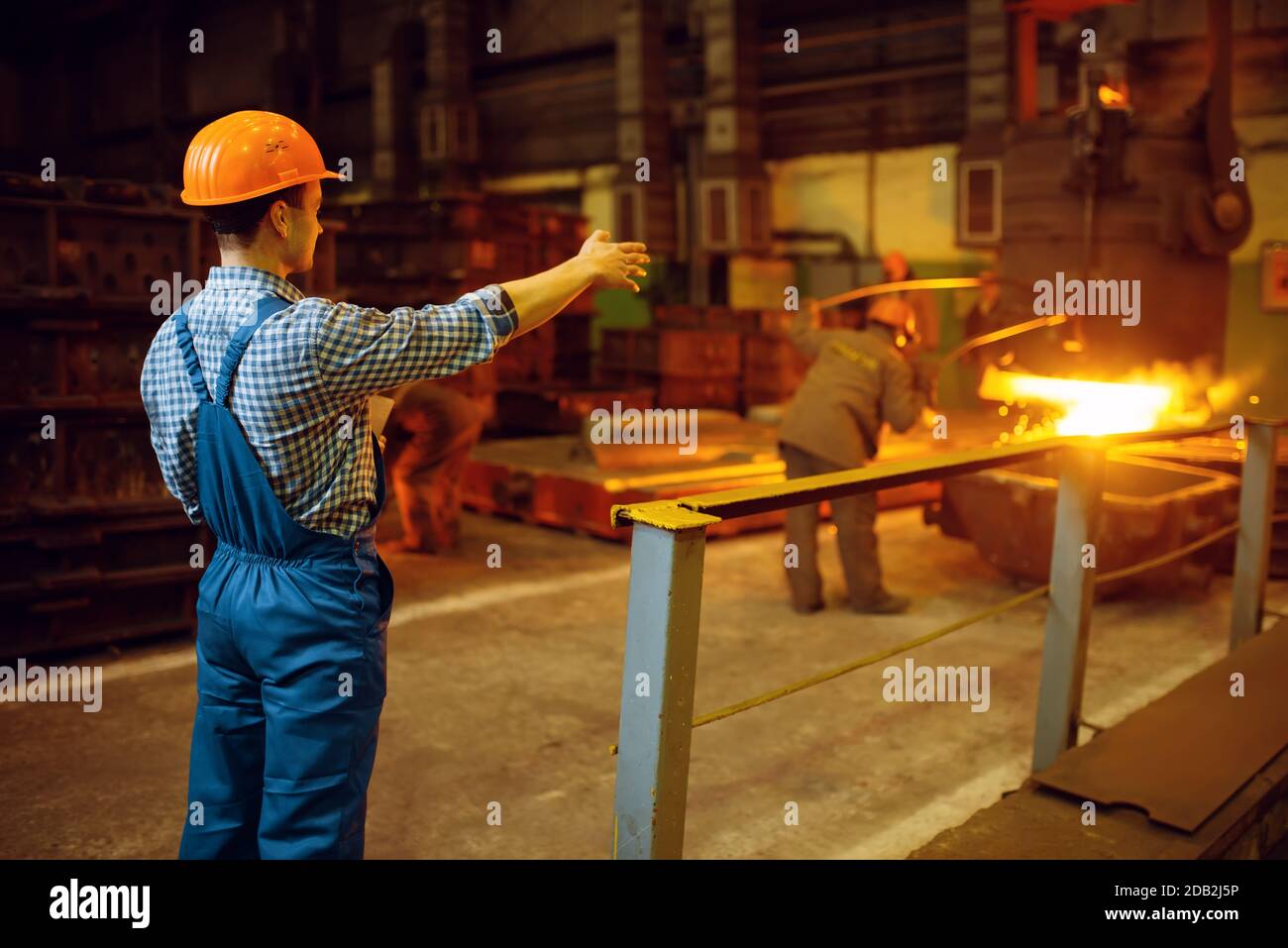 Master looks on steelmaking process in furnace, steel factory ...