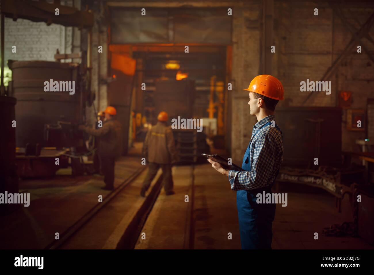 Master looks on steelmaking process in furnace, steel factory ...