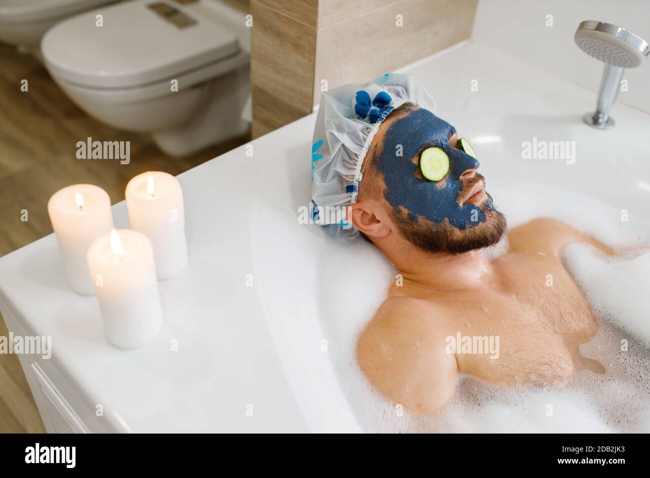 Man applies face mask and relax in bath with foam, morning hygiene ...