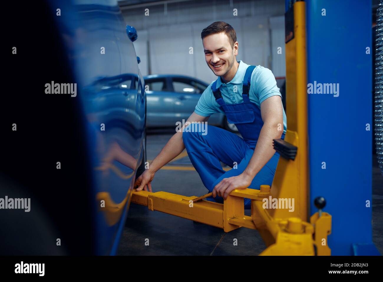 Worker in uniform fix vehicle on lift, car service station. Automobile ...